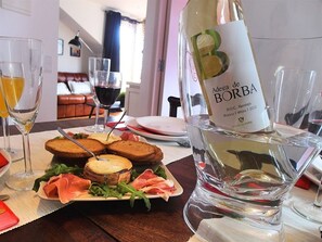 Uma mesa de jantar com uma garrafa de vinho Borda, copos e um prato de comida.