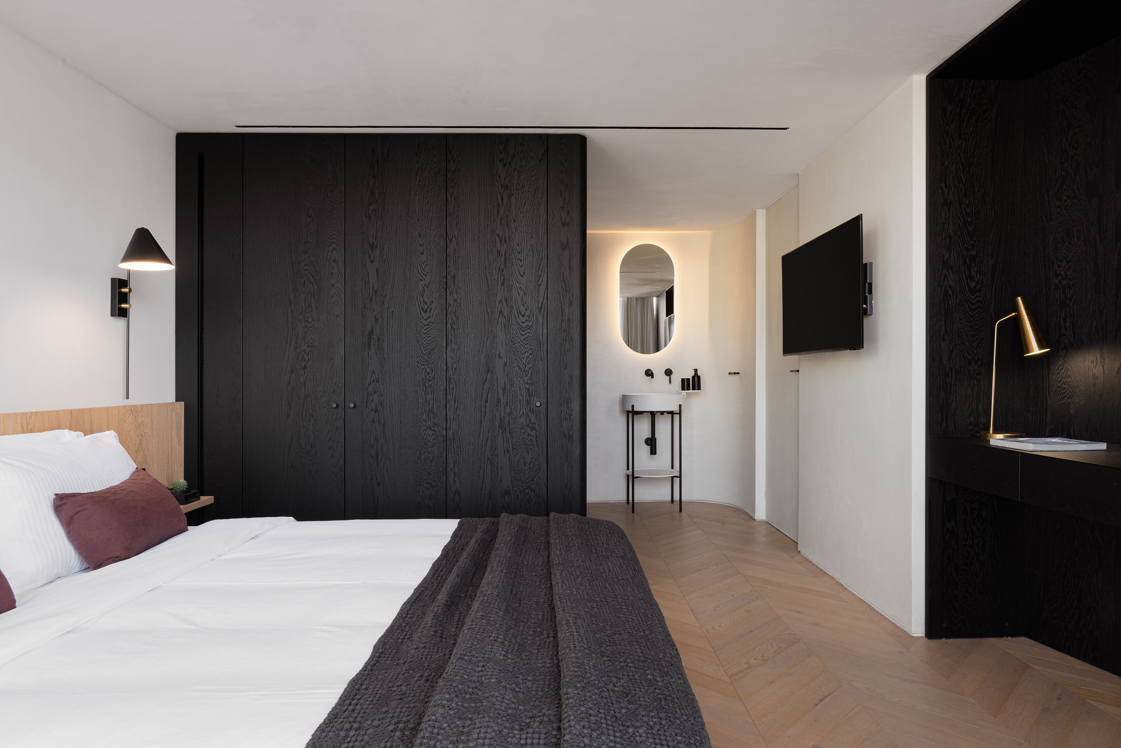 Quarto moderno com uma cama grande, guarda-roupa, toucador com espelho e televisão de tela plana.