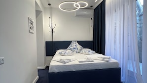 Um quarto moderno com uma cama grande, uma luminária de teto e vista para o exterior.