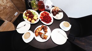 Uma mesa redonda com pratos de comida, um jarro de chá e uma caixa de lenços.