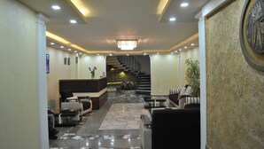 Um hall amplo com balcão de atendimento, área de estar e escada para os andares superiores.