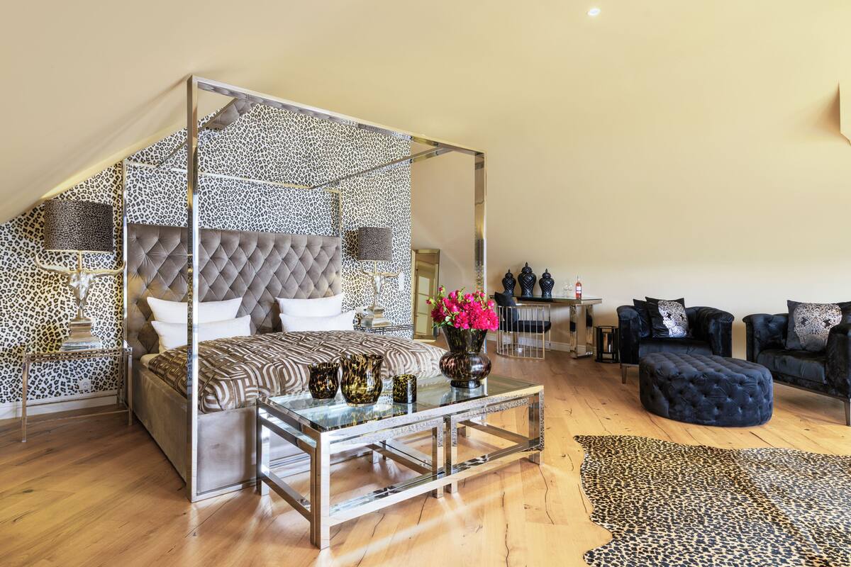 Quarto com uma cama de dossel, uma mesa de centro de vidro e um tapete estampado com padrão de leopardo.