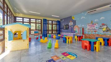 Uma sala de aula com estruturas lúdicas coloridas, mesas e cartazes educativos.