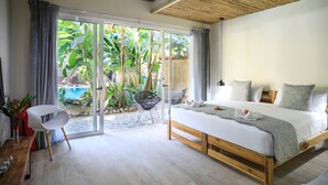 Quarto com cama grande, cabeceira de madeira, porta de vidro que dá para uma piscina e uma cadeira perto da porta.