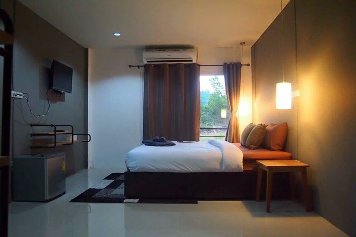 Quarto moderno com cama, mesa de cabeceira e televisão na parede.