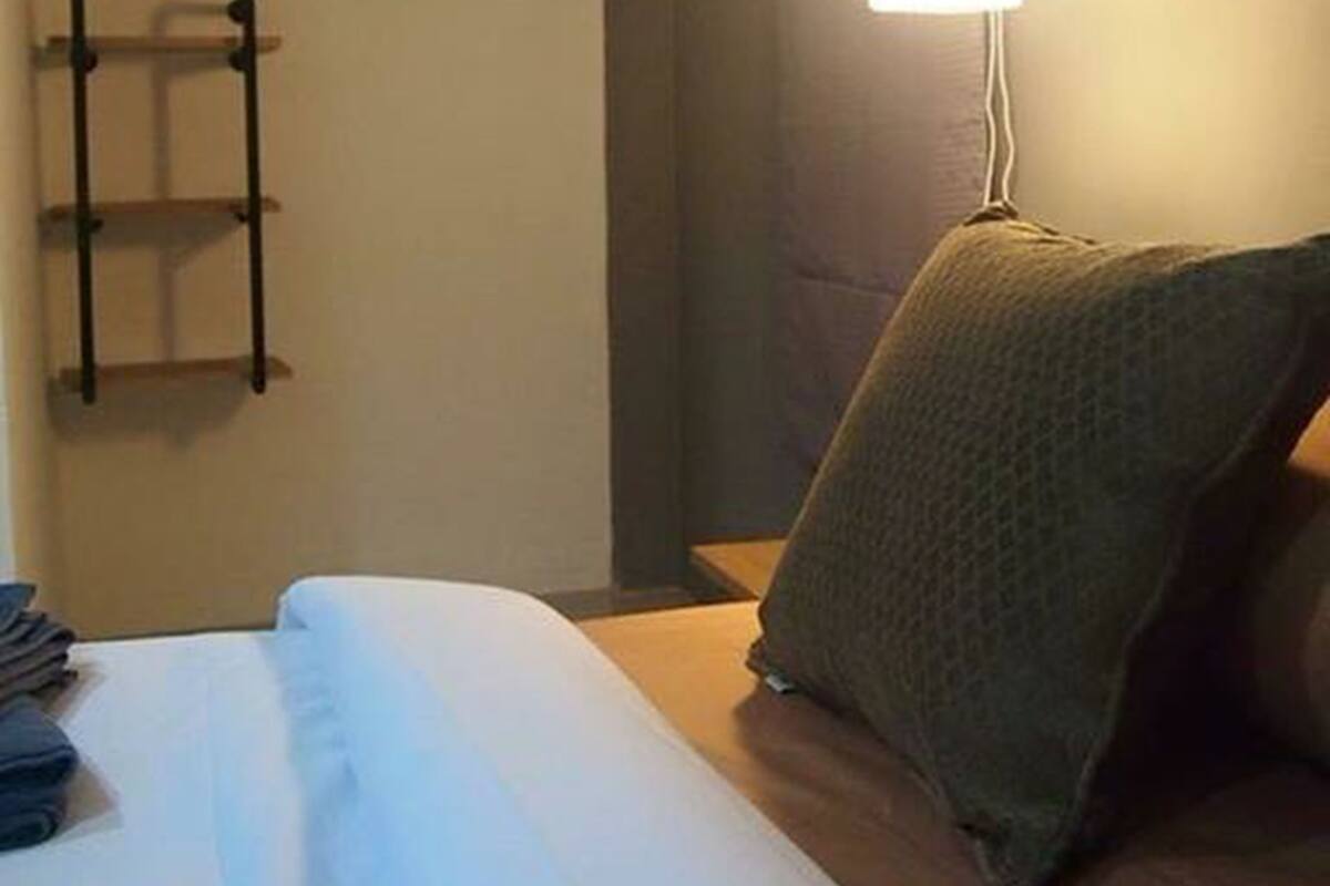 Quarto de hotel com cama, porta-toalhas pendurado e abajur.