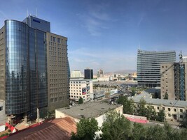 Paisagem urbana com edifícios modernos, incluindo um arranha-céu de vidro curvo e um edifício retangular de vidro.