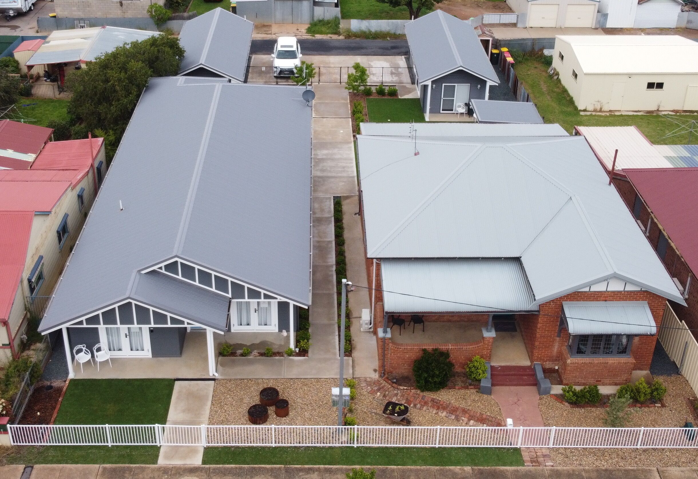Um bairro residencial com duas casas, cada uma com um design de telhado diferente e um pequeno jardim frontal.