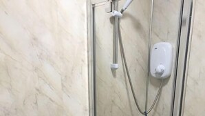 Boxe de vidro com chuveiro manual, dispensador de sabonete e porta de vidro.