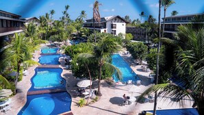Um resort com várias piscinas cercado por palmeiras e espreguiçadeiras.