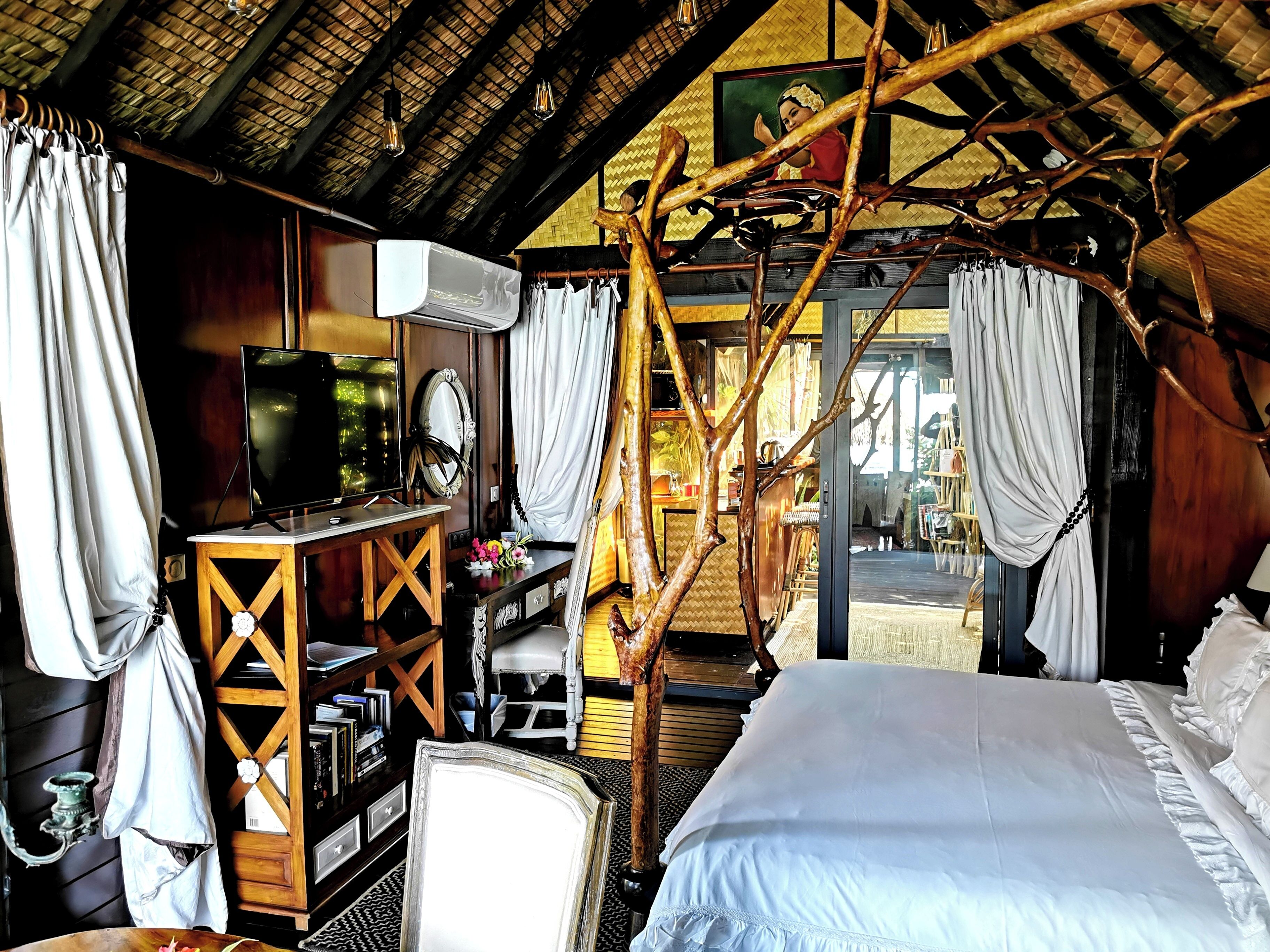 Quarto com cama, televisão, armário de madeira e área de refeições com mesa e cadeiras.