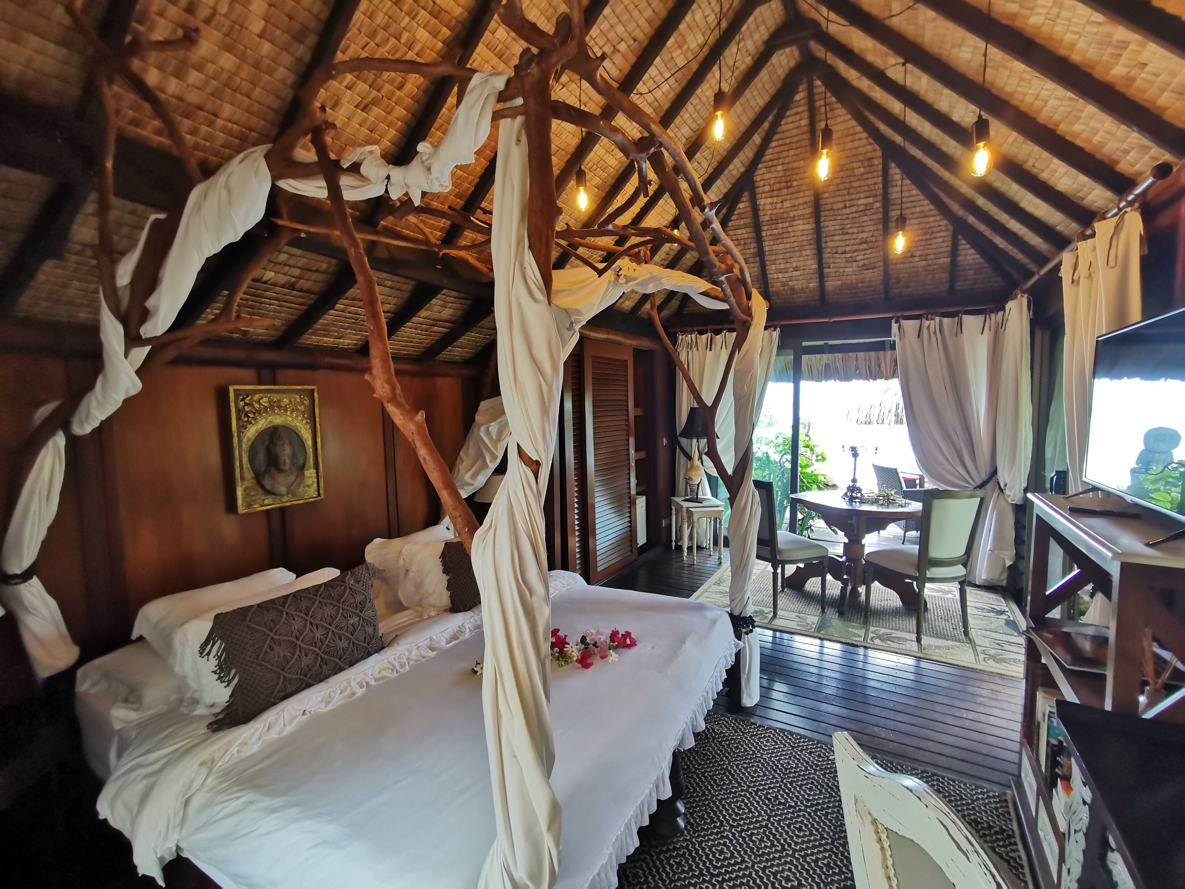 Quarto com cama, televisão e área de refeições.