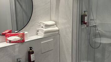 Um banheiro moderno com um espelho grande, pia, vaso sanitário e chuveiro com divisória de vidro.