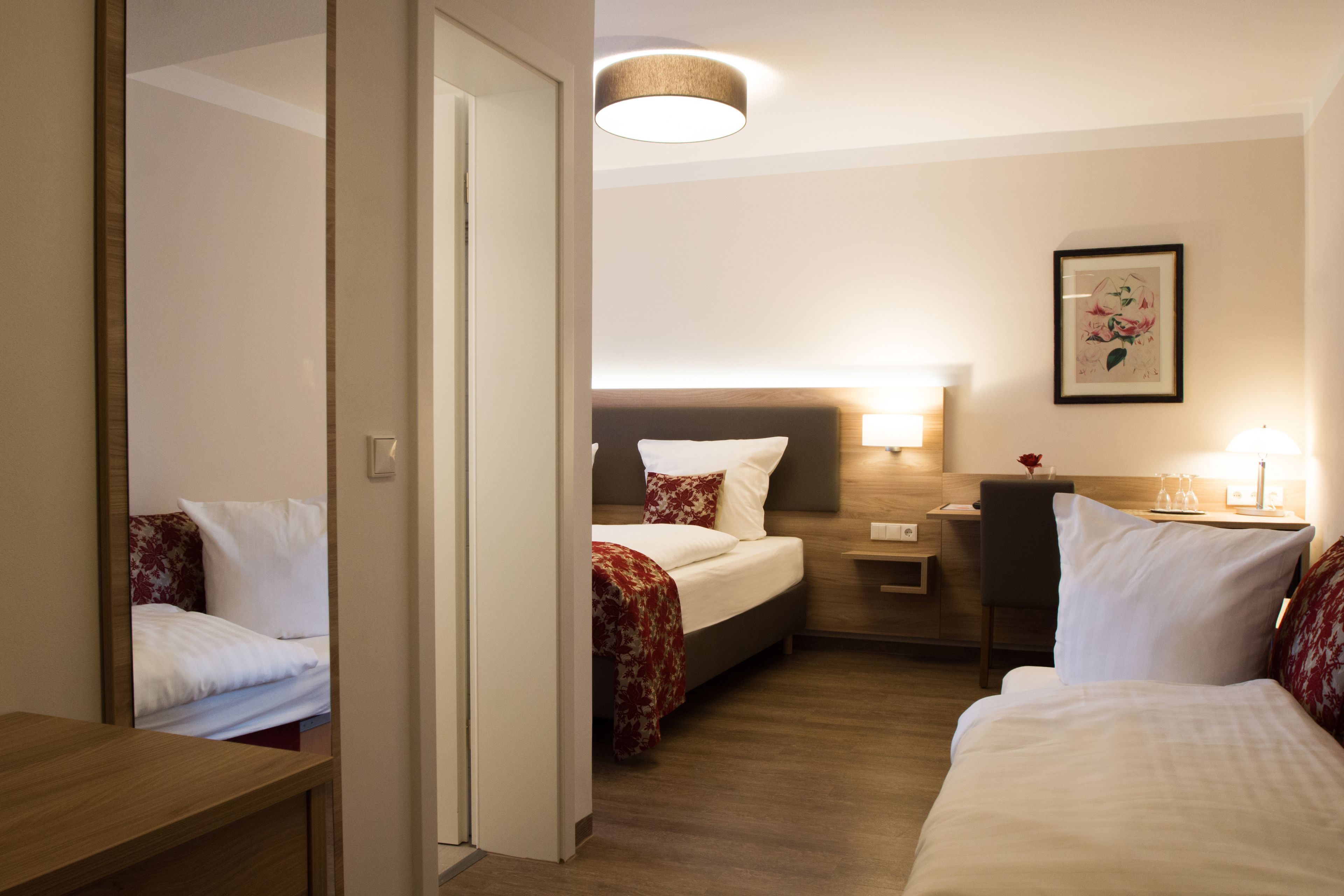 Quarto de hotel com cama, mesa de cabeceira, abajur e uma moldura na parede.