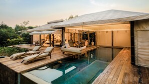 Uma área à beira da piscina com espreguiçadeiras e um espaço de estar coberto.