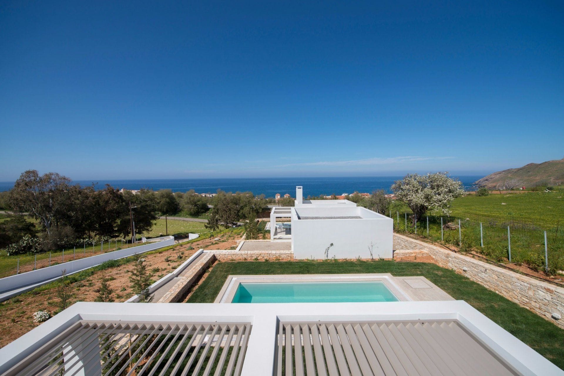 Uma casa moderna com piscina, vista clara para o oceano e jardim cercado.