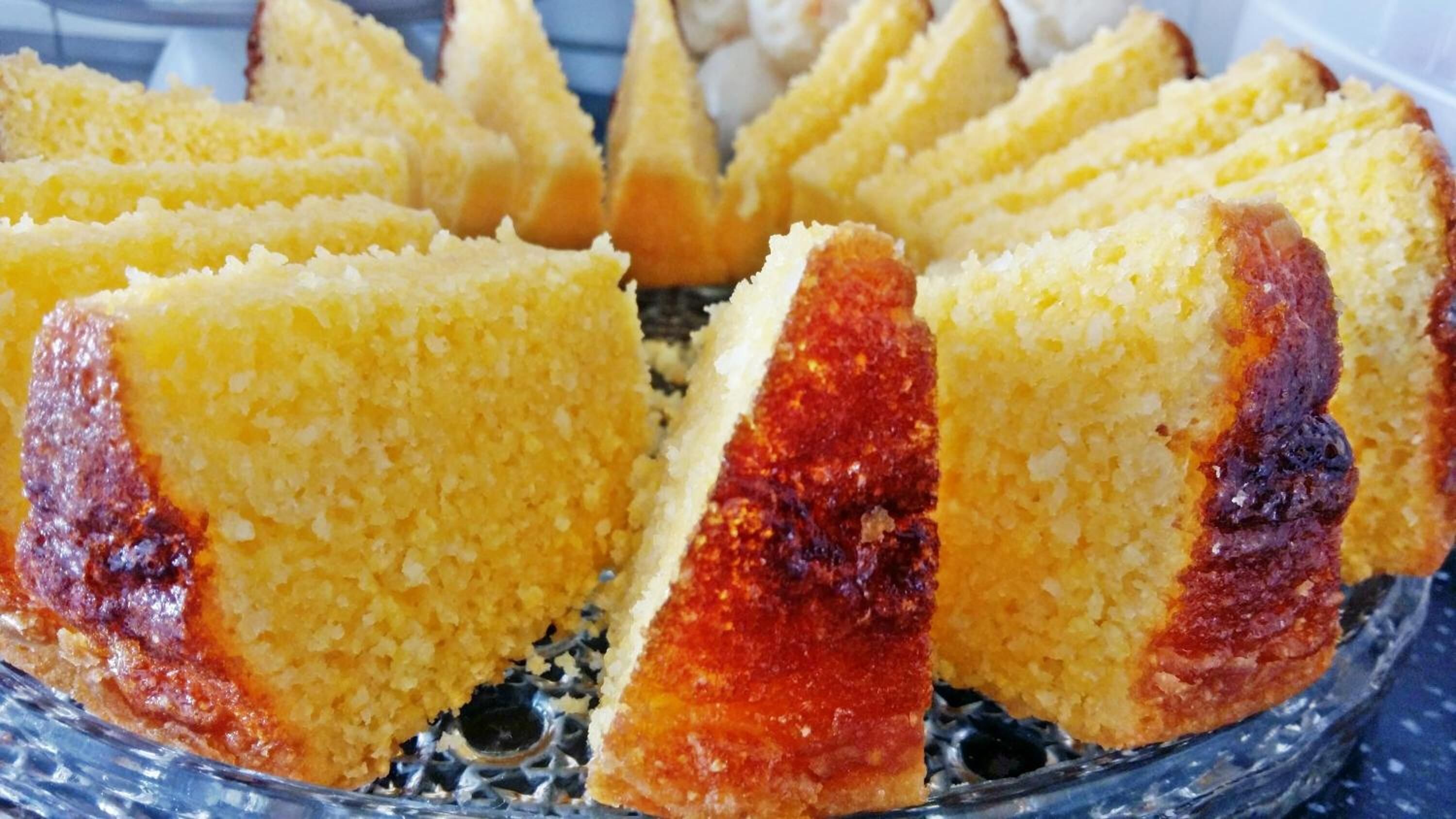 Uma travessa de vidro com vários pedaços de bolo triangulares, alguns com crosta dourada.