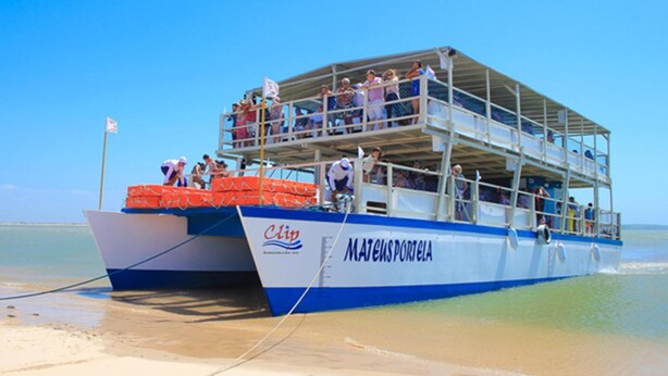 Um ferryboat com vários andares e passageiros, atracado na praia.