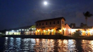 Um edifício à beira-mar com arcos iluminados e reflexo na água.