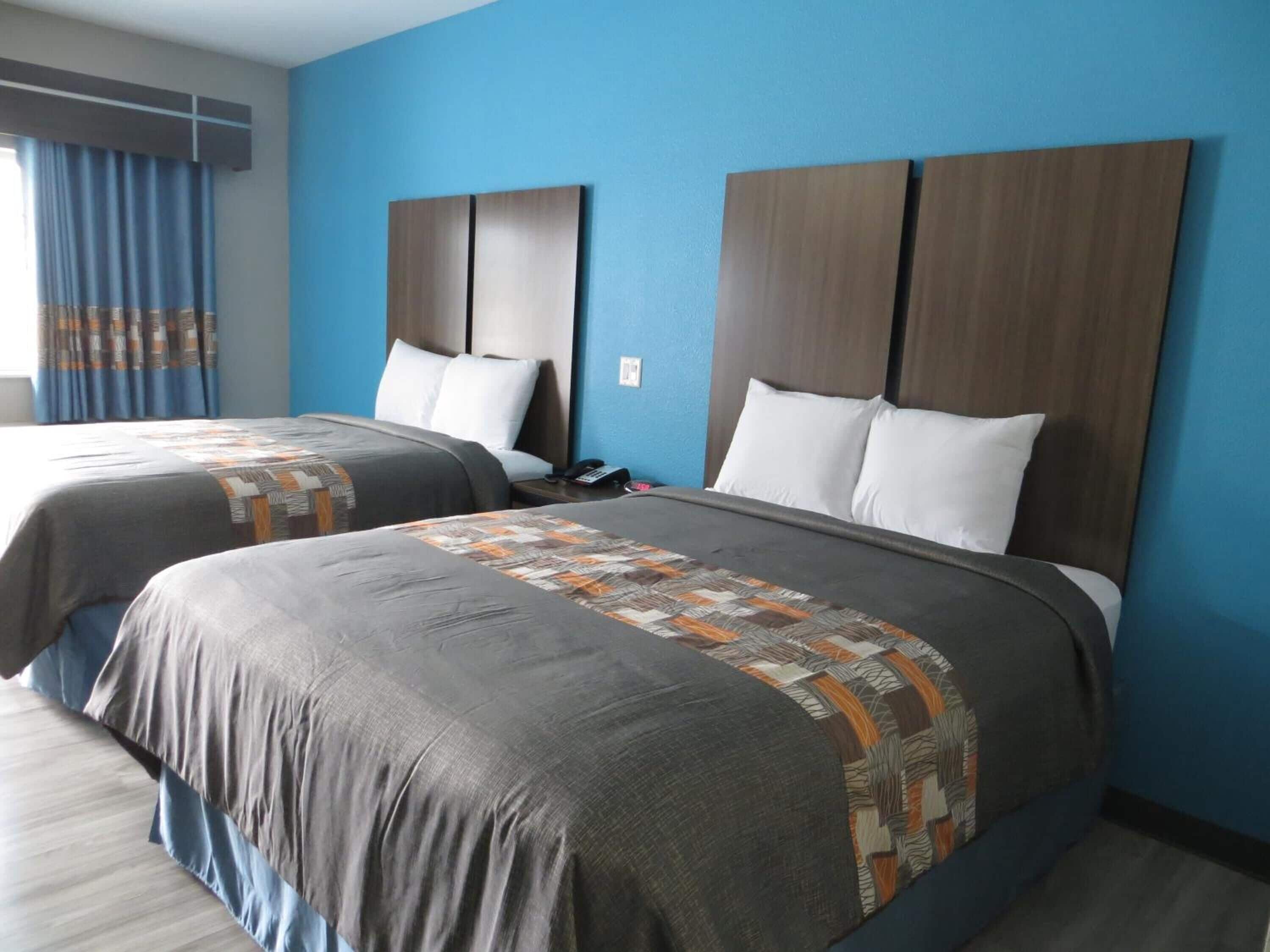 Quarto de hotel com duas camas, cada uma com cabeceira, telefone e mesa de cabeceira.