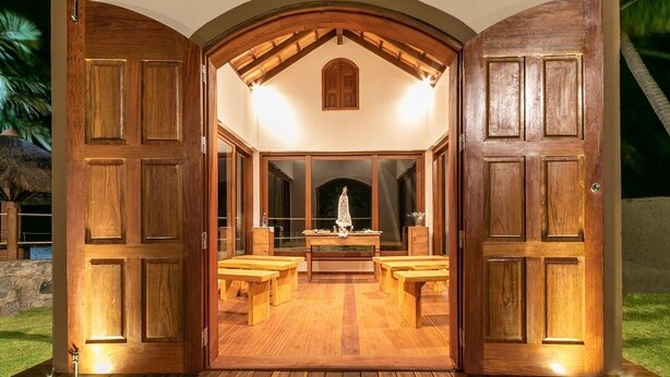 Estrutura de madeira aberta com bancos e um altar central, sugerindo um local religioso ou espiritual.