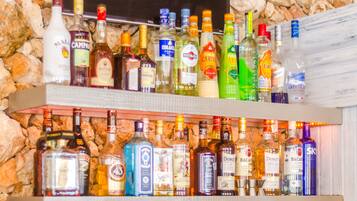 Um bar com várias prateleiras cheias de garrafas de bebidas alcoólicas.