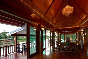 Uma sala de jantar ampla, com uma mesa grande e cadeiras, painéis de madeira e um lustre.