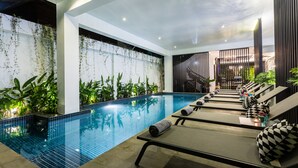 Uma área interna de piscina moderna com cadeiras de lounge e um mural no teto.