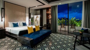 Quarto moderno com uma cama grande, varanda com plantas e vista da cidade à noite.