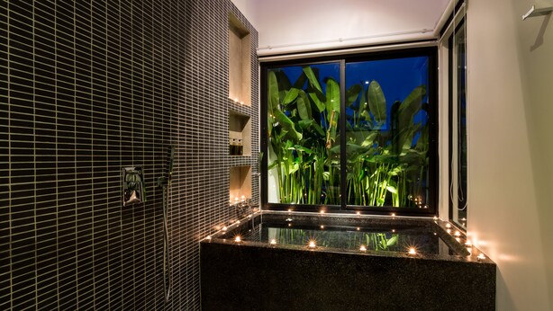 Uma casa de banho moderna com uma janela ampla, uma banheira embutida e um revestimento de azulejos.