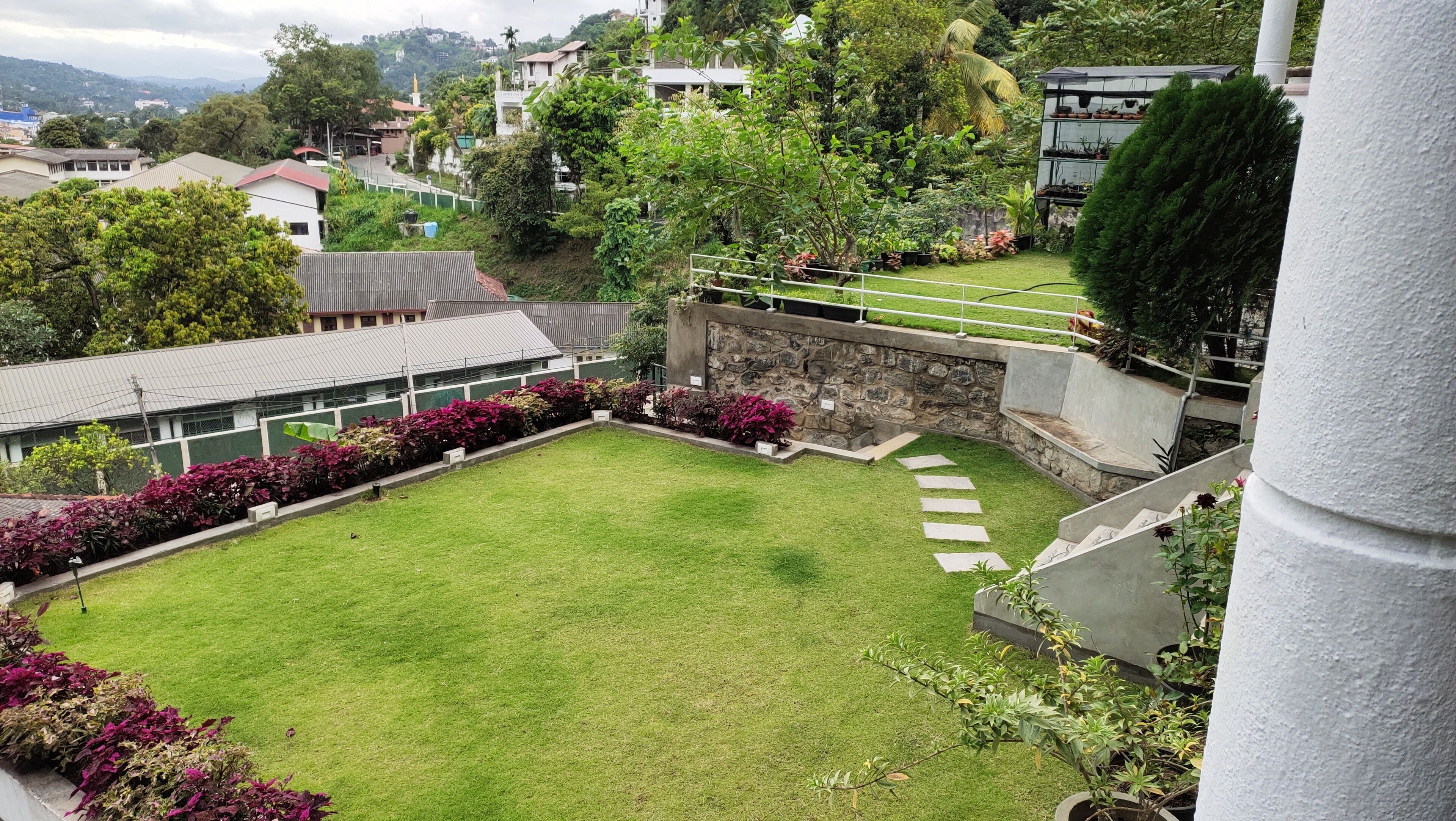 Pátio com gramado, parede de pedra e plantas em vasos.