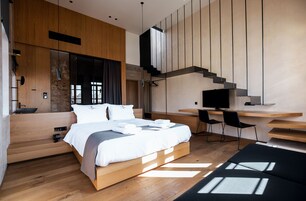 Quarto moderno com cama de madeira, escrivaninha e escada.