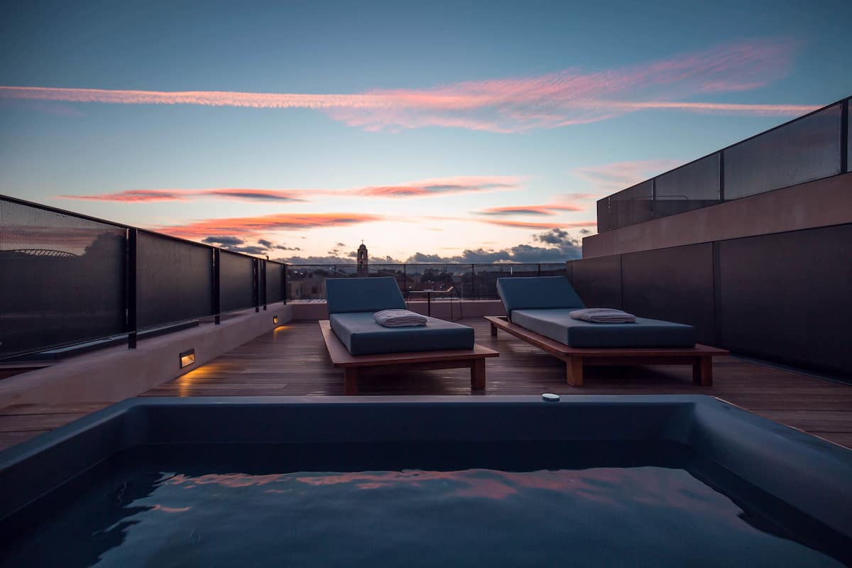 Terraço no telhado com duas espreguiçadeiras e uma banheira de hidromassagem.