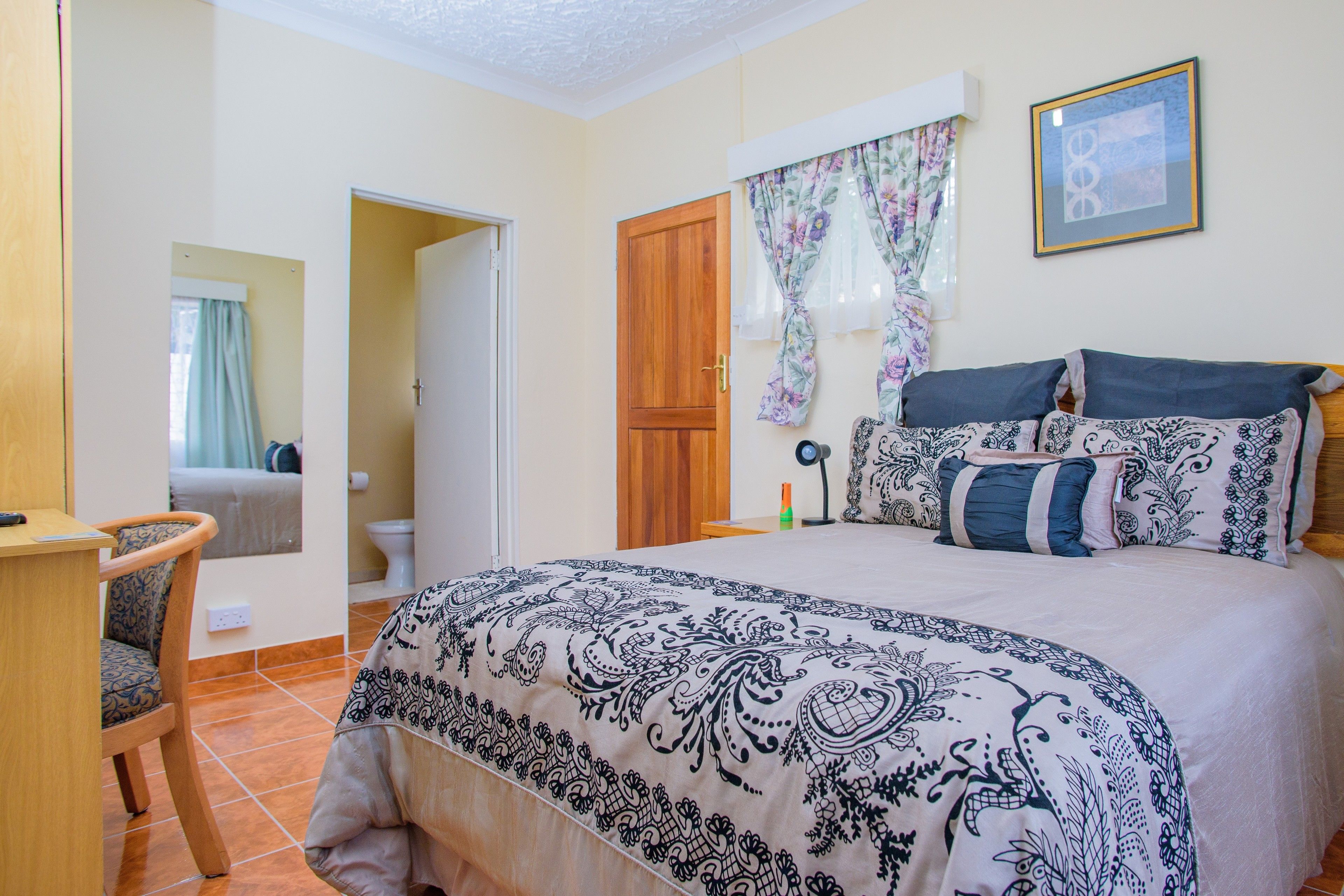 Quarto com cama, escrivaninha, cadeira, guarda-roupa e banheiro.