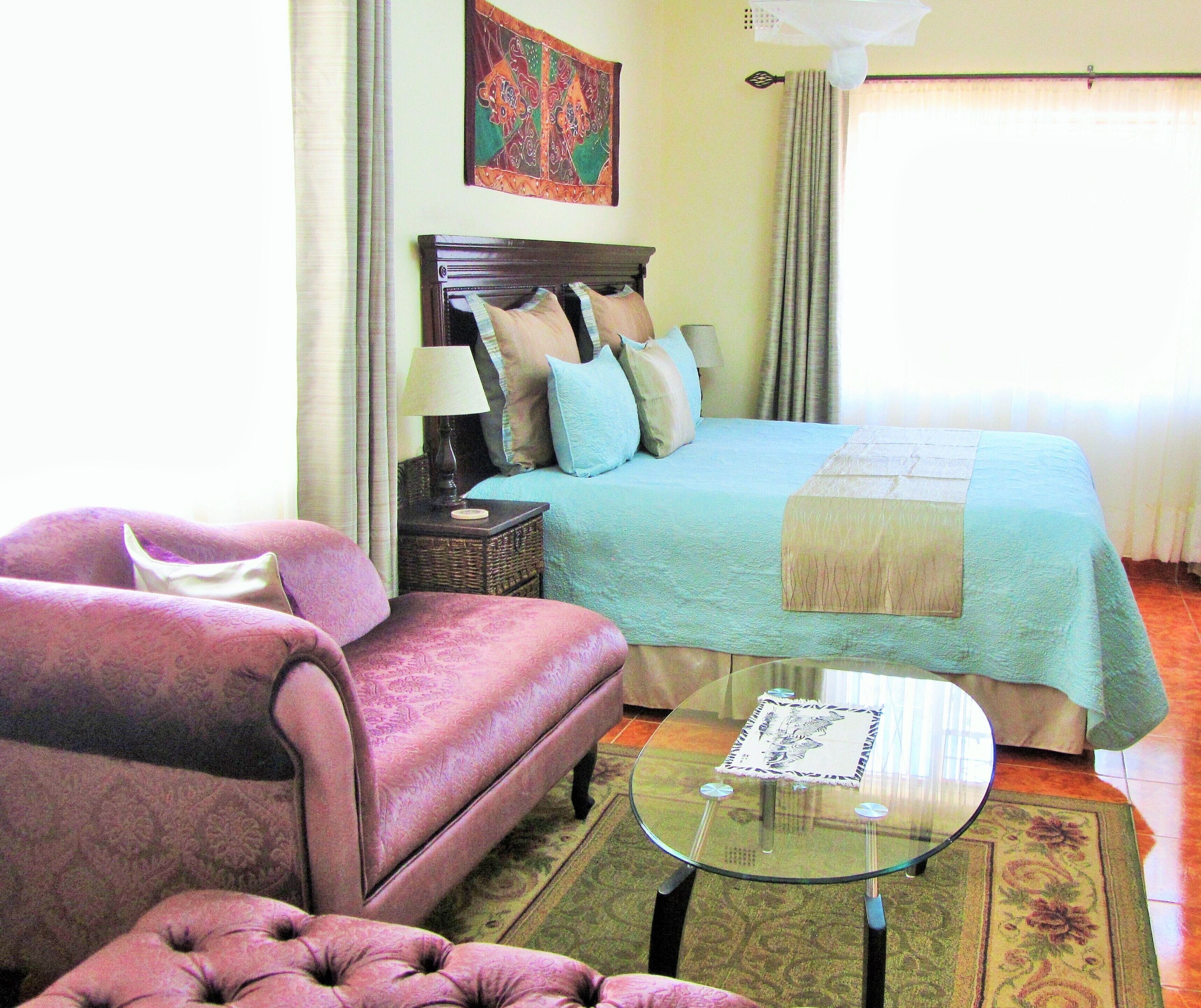 Um quarto com cama, uma cadeira, mesa de cabeceira e uma pequena mesa.