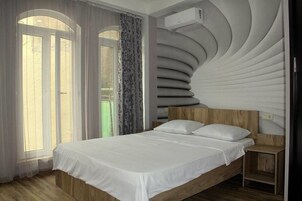 Quarto com cama, cabeceira de madeira, mesa de cabeceira e janela com cortinas.
