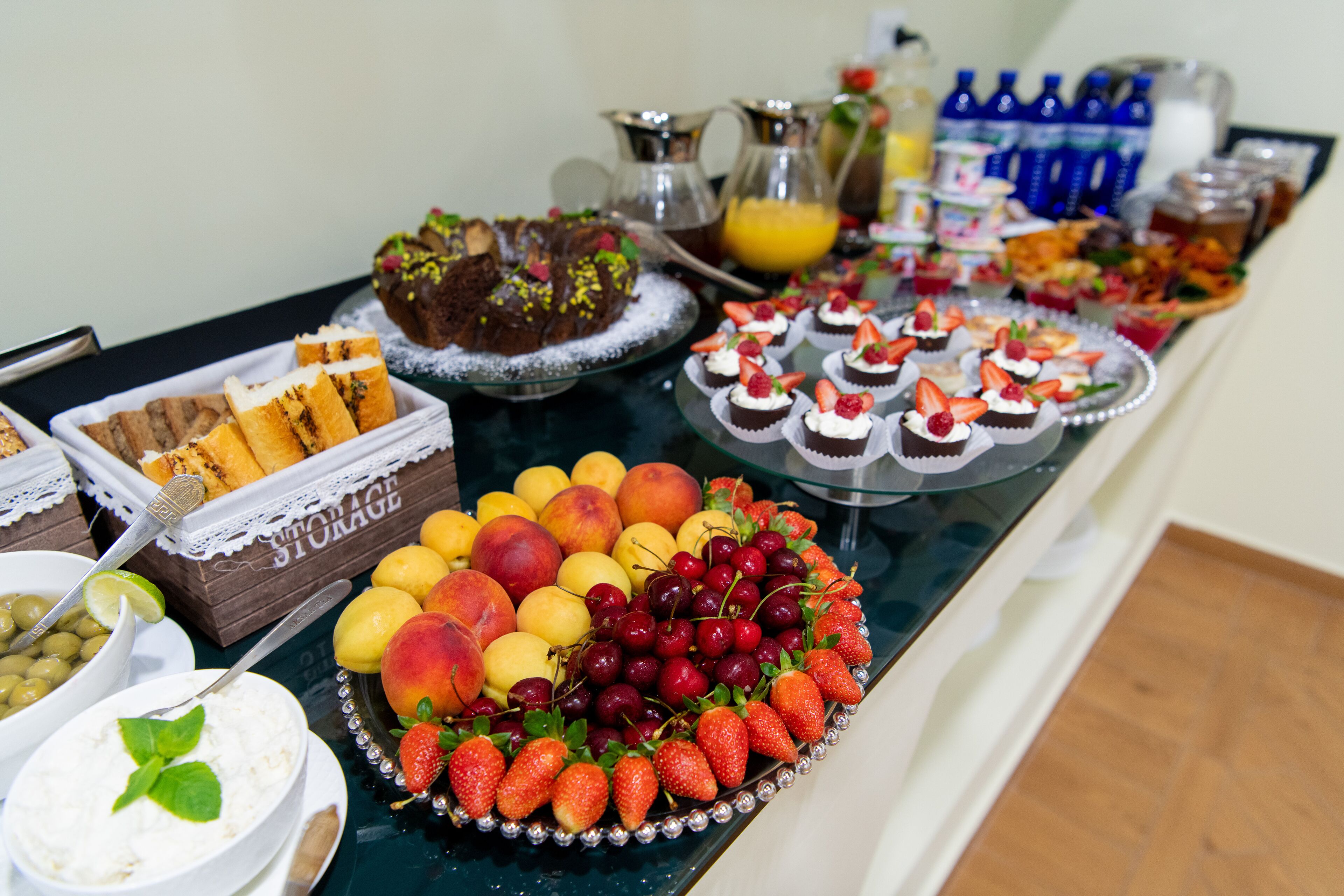 Buffet com diversas opções de comida, incluindo frutas, doces e bebidas.