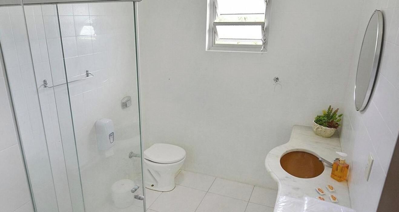 Casa de banho com cabine de chuveiro em vidro, sanita e lavatório.