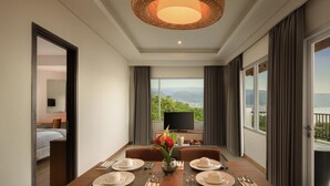 Uma sala de jantar com uma mesa posta para quatro pessoas, uma televisão e vista para o exterior.