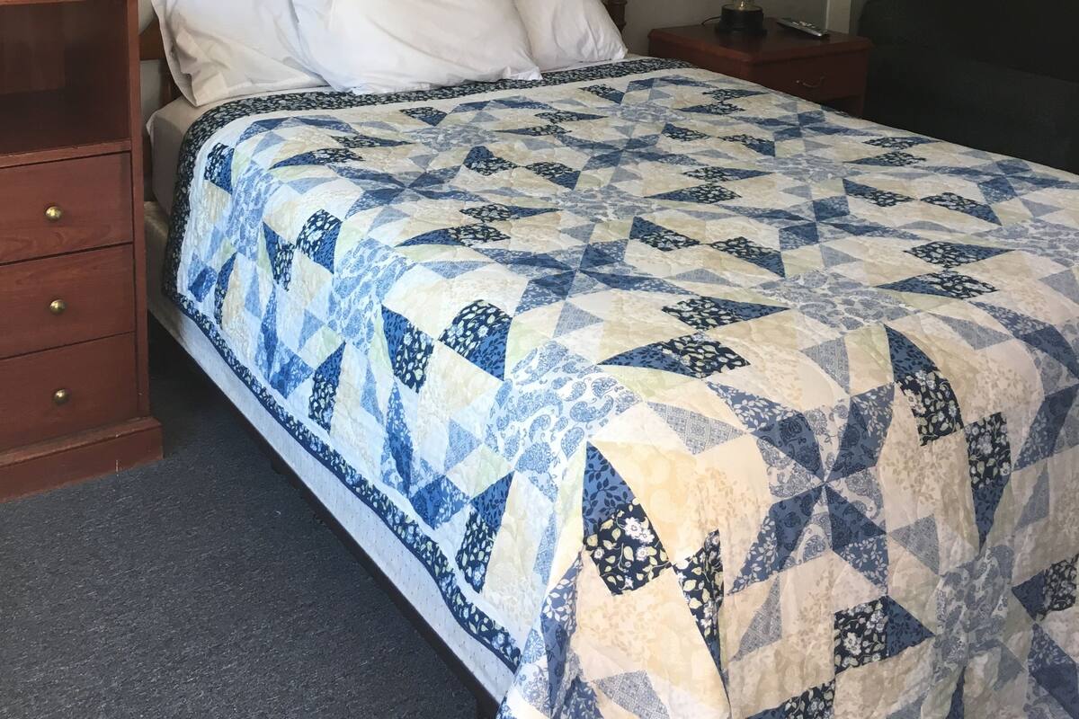 Quarto com cama, mesa de cabeceira, abajur, cômoda e interruptor de luz na parede.