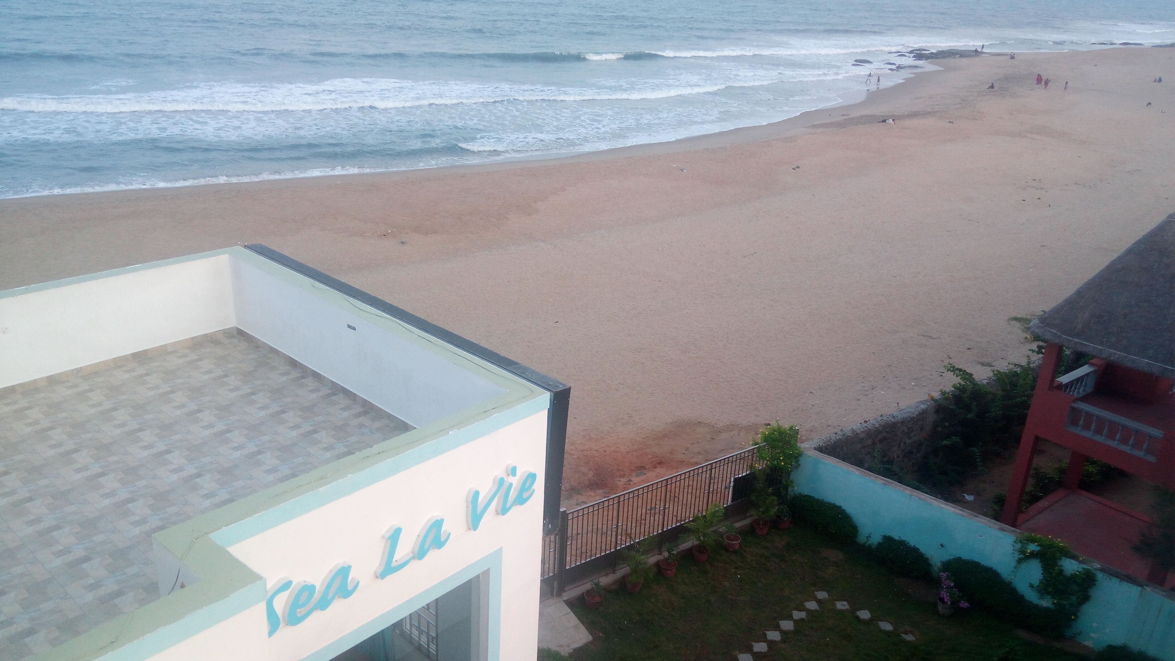 Vista da praia a partir de um edifício com uma placa que diz 'Sea La Vie'.