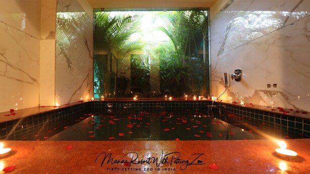 Uma área de spa com piscina, velas e paisagem tropical.