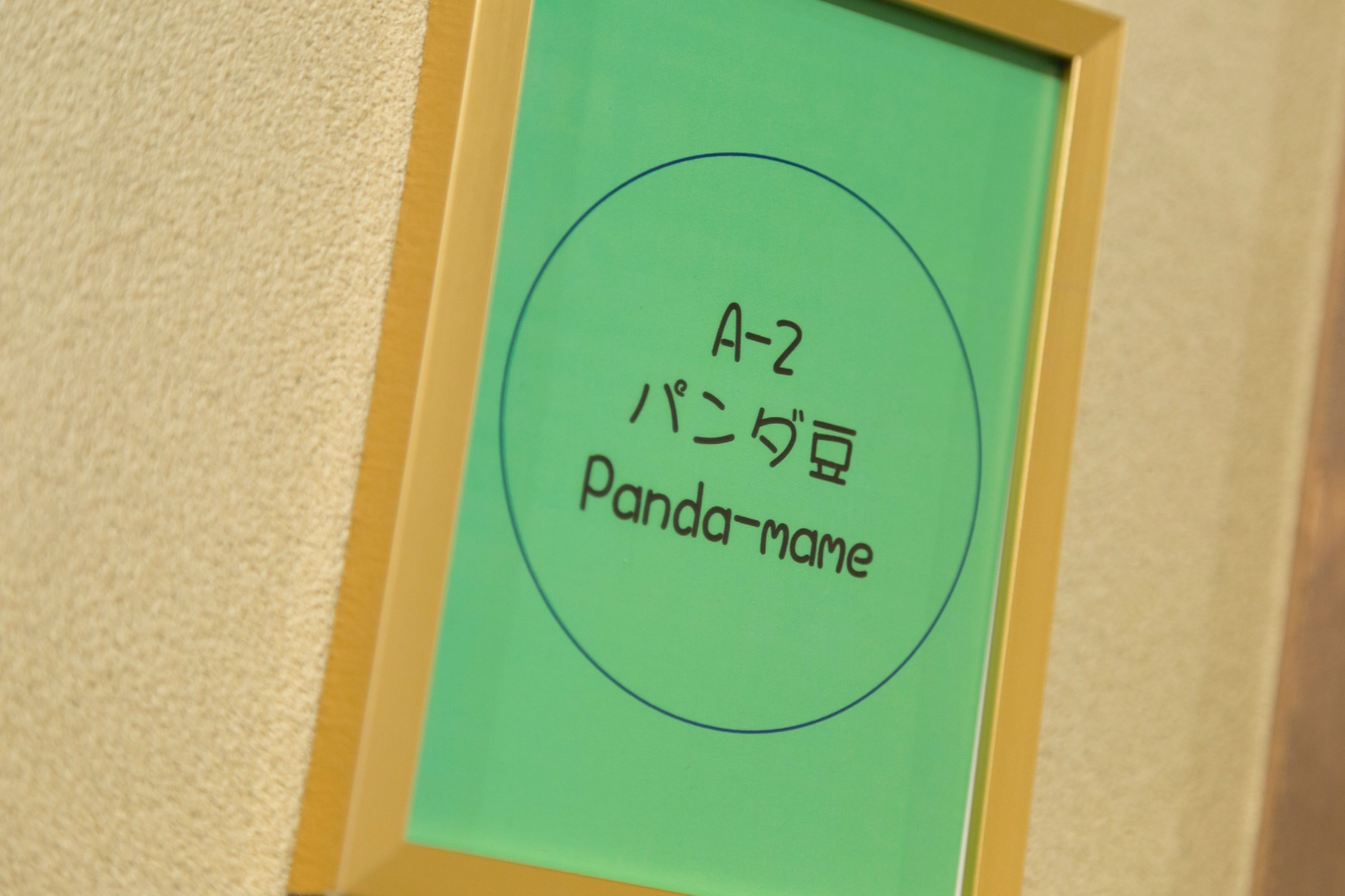 Uma placa emoldurada com texto em japonês e o nome 'Panda-mame' em inglês.