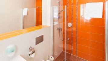 Uma casa de banho moderna com chuveiro em cabine de vidro, lavatório branco e sanita.