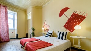 Um quarto com uma cama e muitos travesseiros listrados vermelhos e brancos.