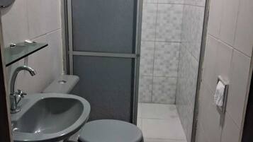 Um banheiro pequeno com pia, vaso sanitário e chuveiro.