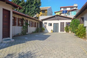 Um pátio com pavimentação hexagonal, edifícios com persianas marrons e uma antena parabólica.