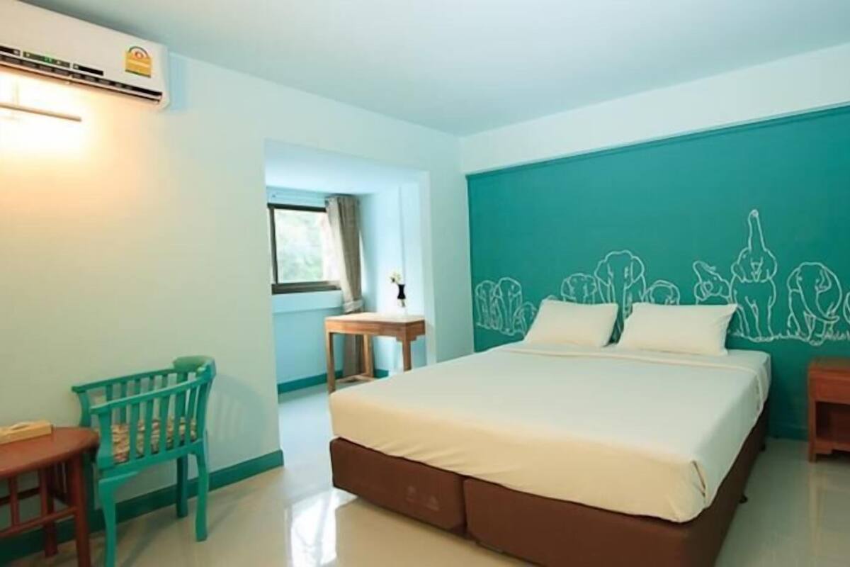 Quarto com cama, escrivaninha, cadeira e parede com desenho de linha branca.