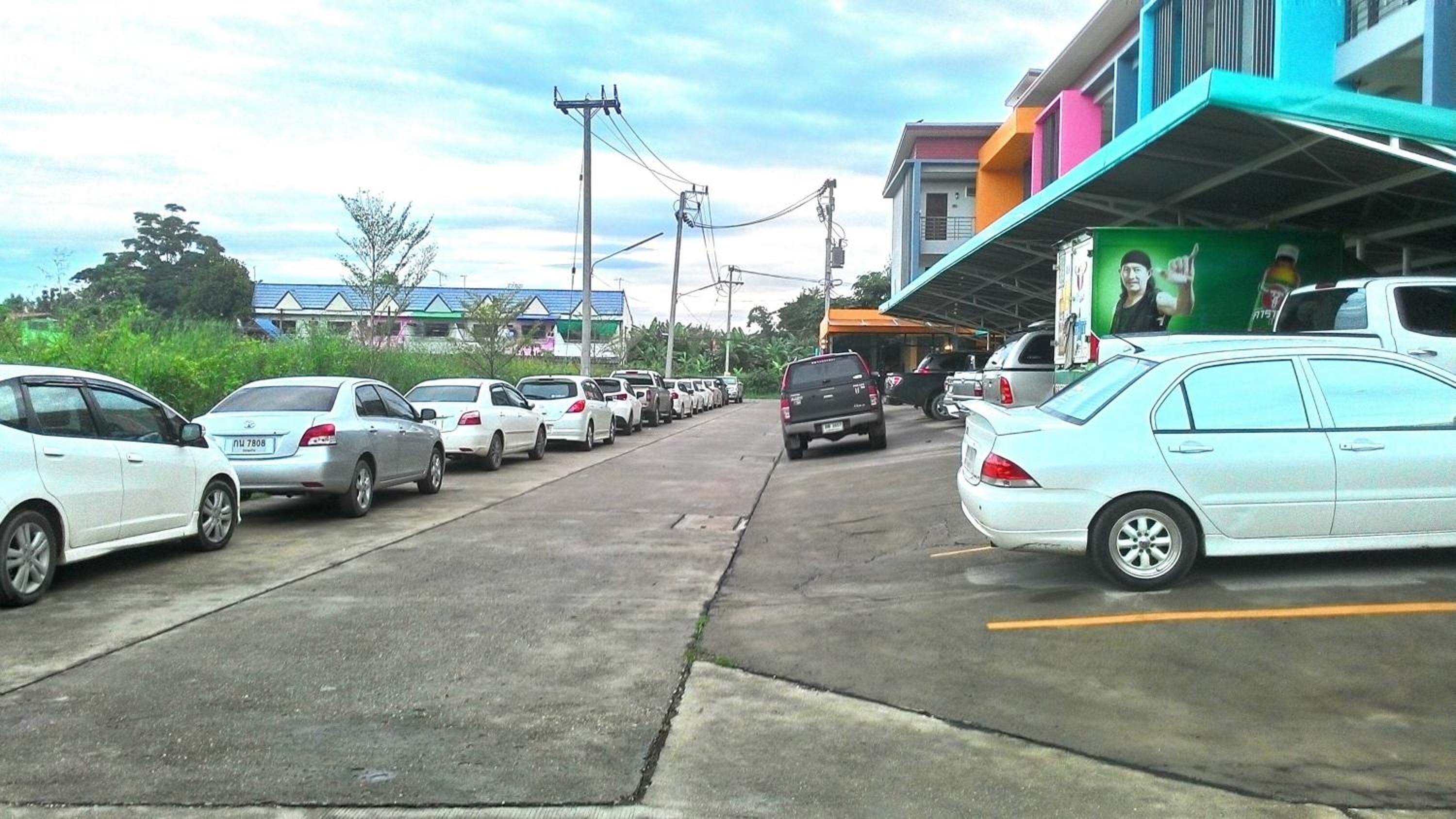 Rua com carros estacionados e edifícios com fachadas coloridas.