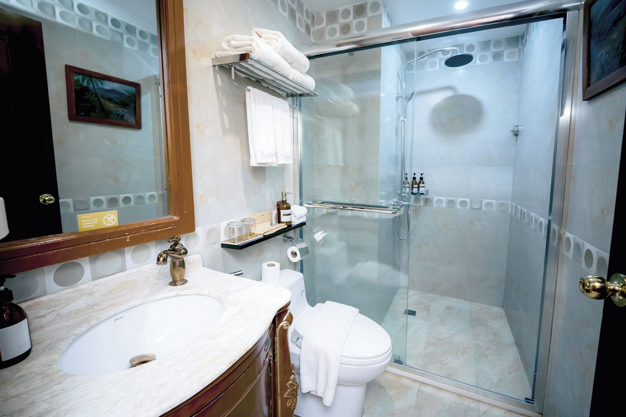 Casa de banho com cabine de duche de vidro, lavatório com bancada de mármore e sanita.